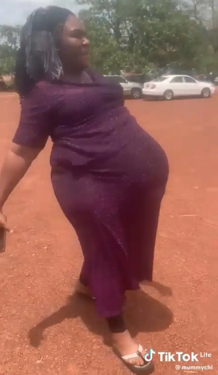 Nigerian woman walks on the road with huge baby bump